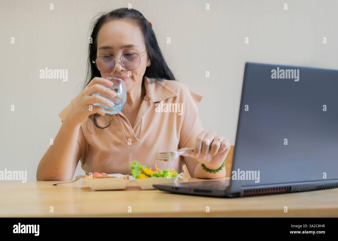 Happy Asian woman enjoying healthy boxed food order delivered to worklace, side view. Healthy ...