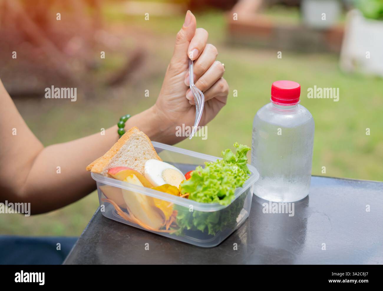 Side view close up business woman eating salad from her lunch box ...