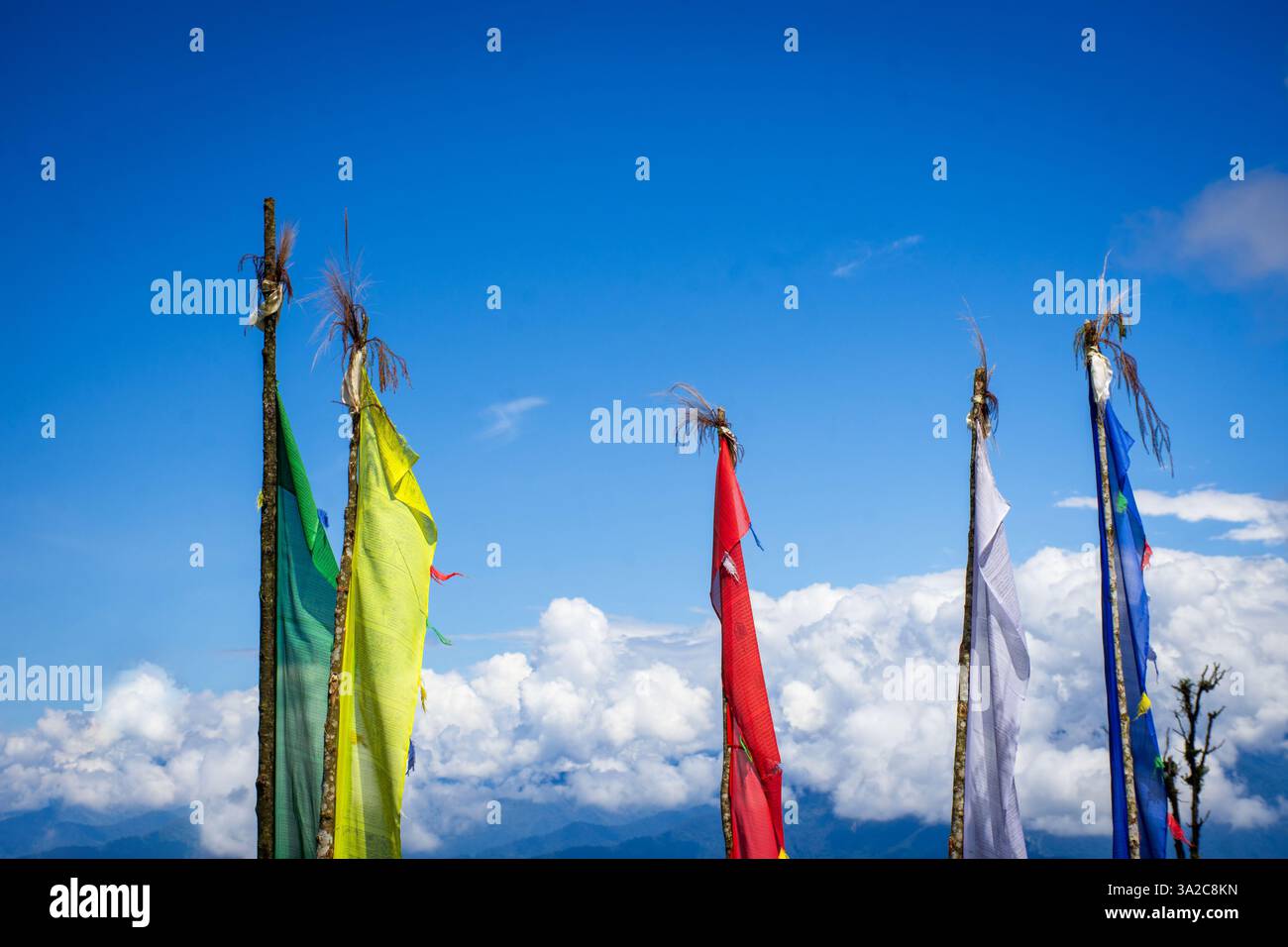 Vibrant red, yellow, and green prayer flags wave on poles, contrasting ...