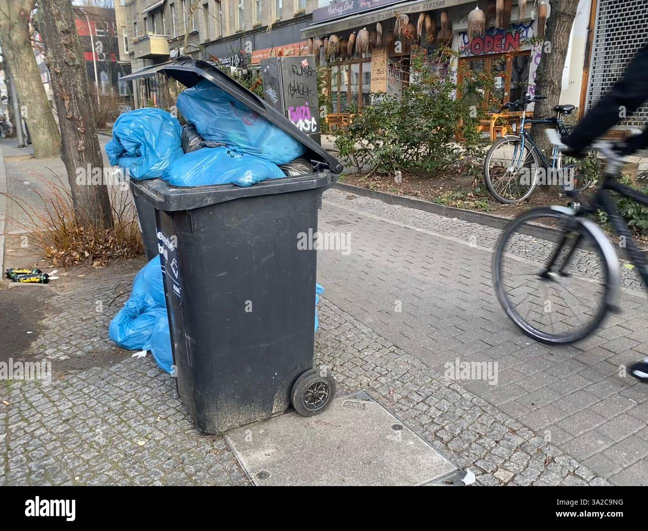 Berlin, Germany. 13th Mar, 2025. An overflowing garbage can stands on a ...