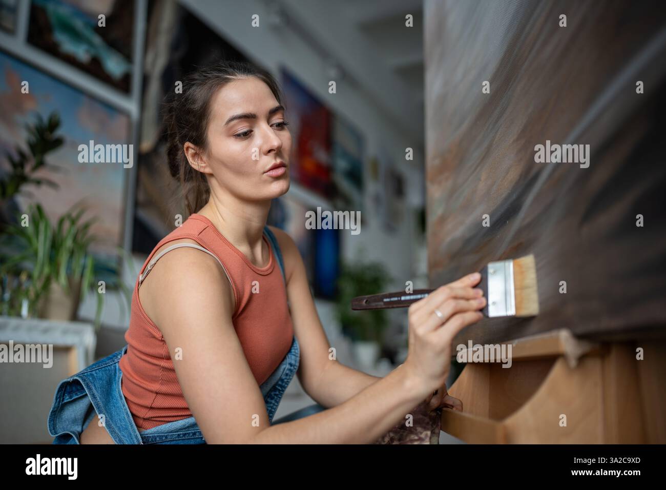 Female artist confidently wields wide brush, wiping canvas from dirt ...