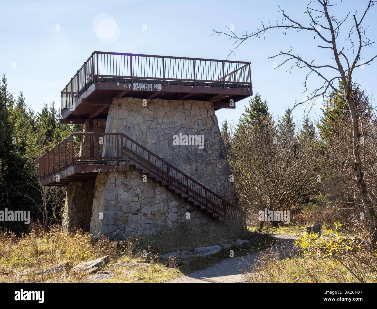 A rugged stone watchtower rises proudly amidst a sunlit forest, gazing ...