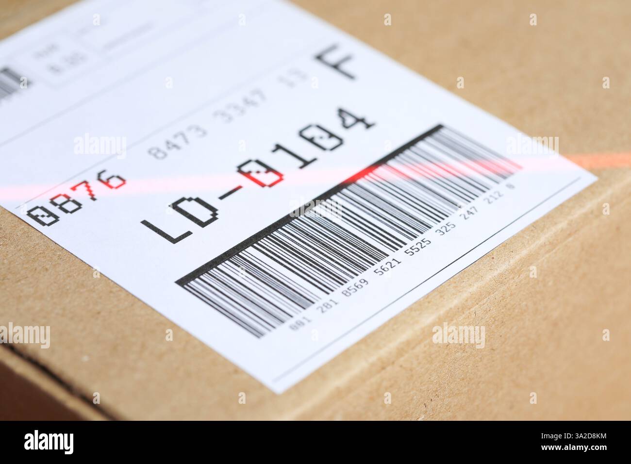 Parcel with label, closeup. Red laser light on barcode for scanning ...