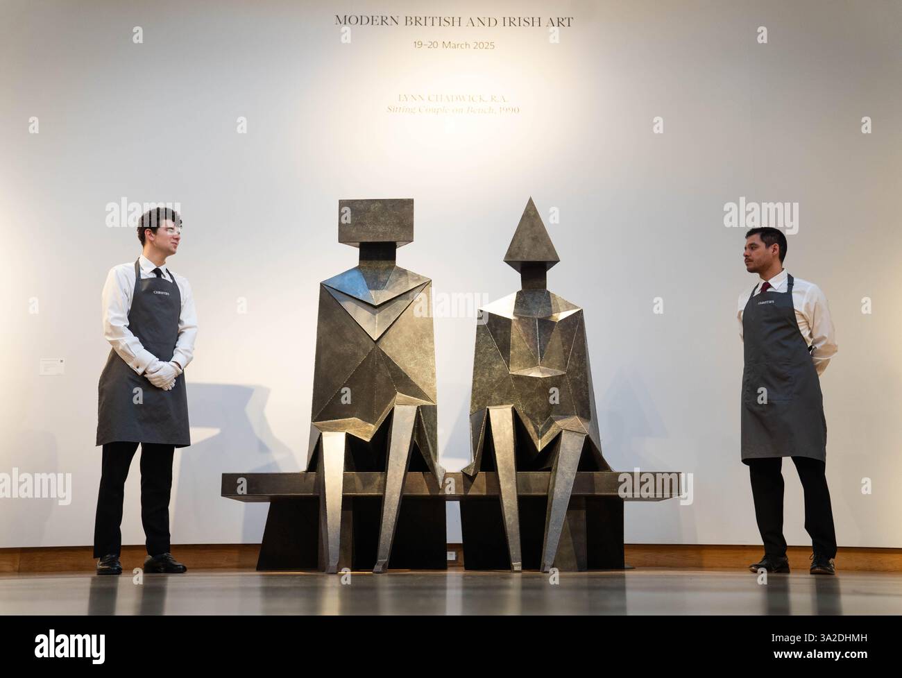 Art handlers stand near Lynn Chadwick's 'Sitting Couple on Bench ...
