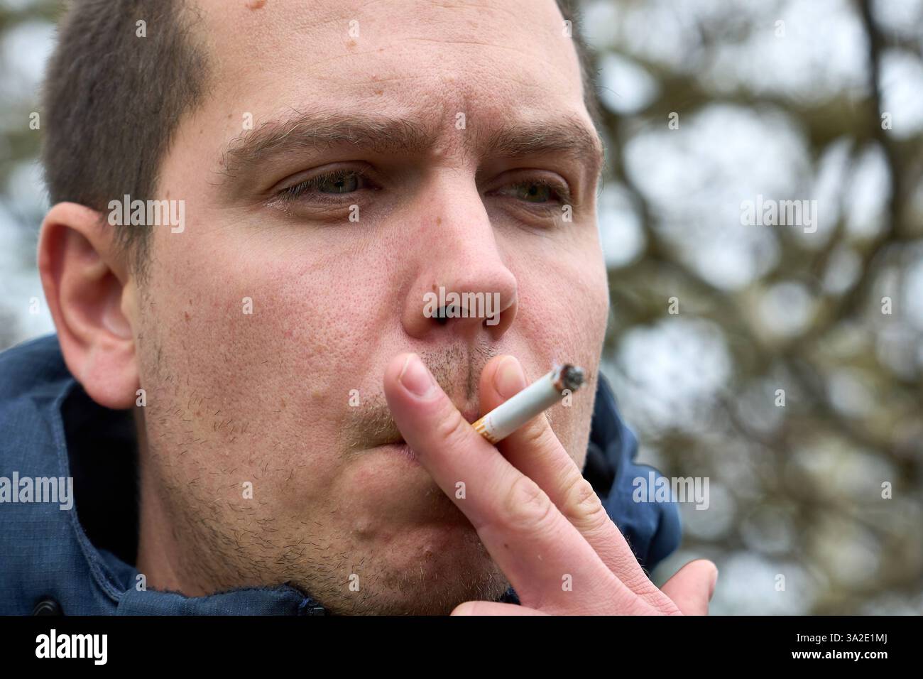 Bavaria, Germany - March 13, 2025: A young man smokes a cigarette ...