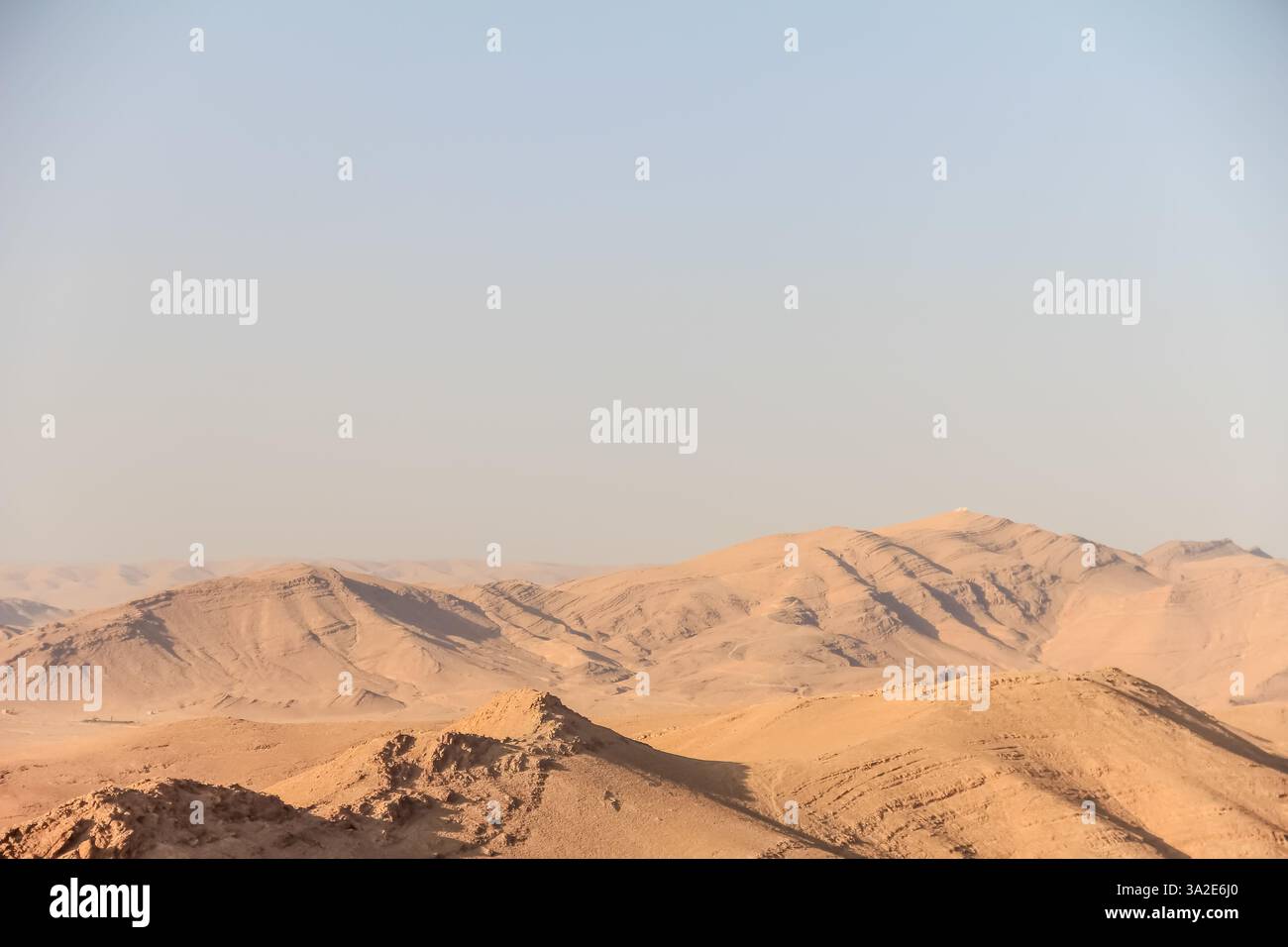 A wide and arid desert landscape showcasing rugged terrain and a hazy ...