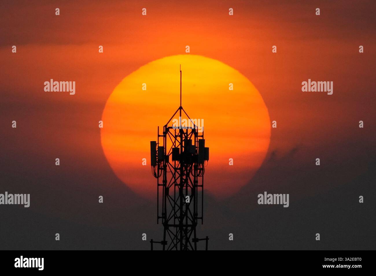 The sun sets behind a communications tower in Quezon city, Philippines ...
