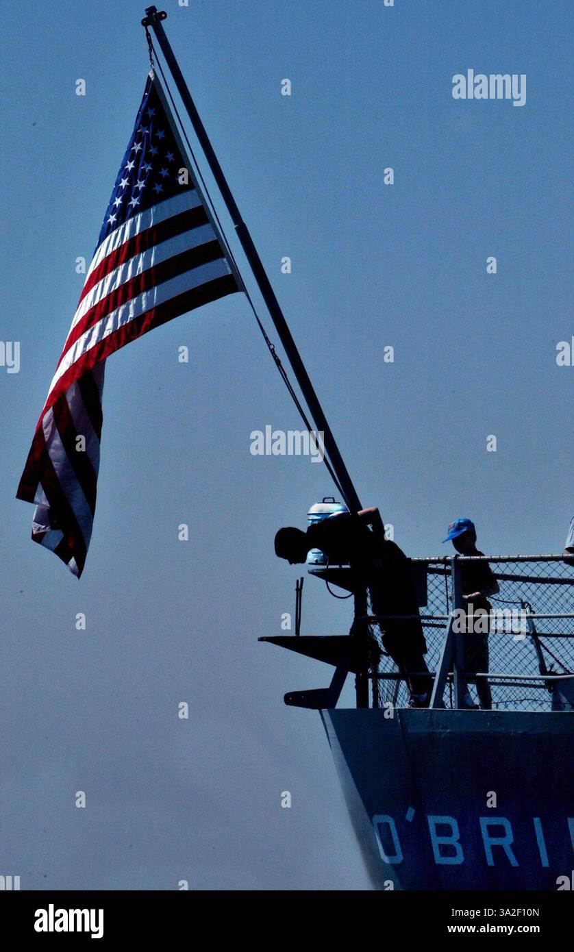A visitor to the ship looks over the stern of the boat with the colors ...
