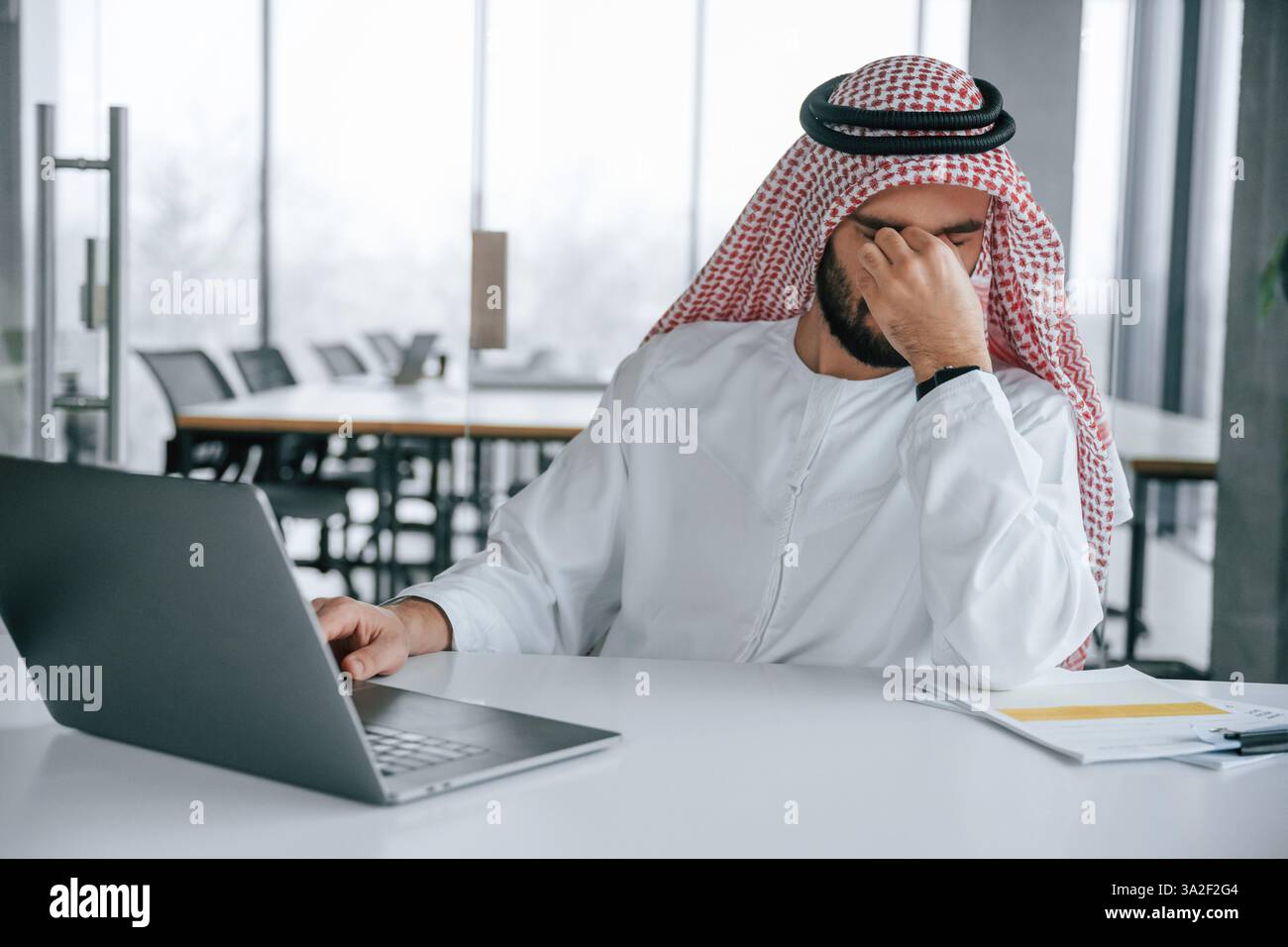 Feeling tired. Sitting by table with laptop. Successful Muslim ...