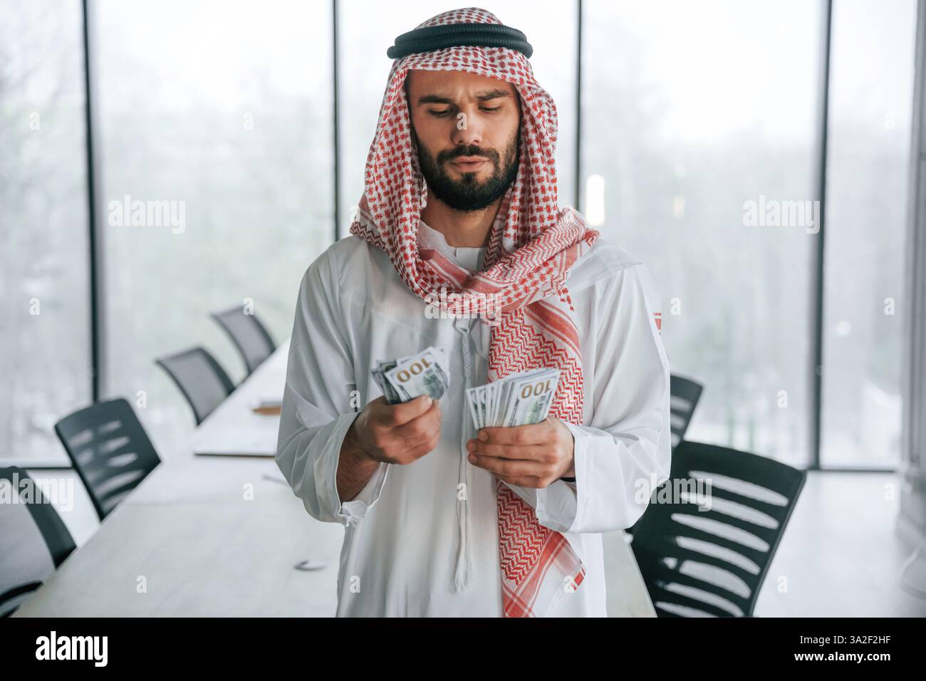 Holding money in hands. Successful Muslim businessman in traditional ...