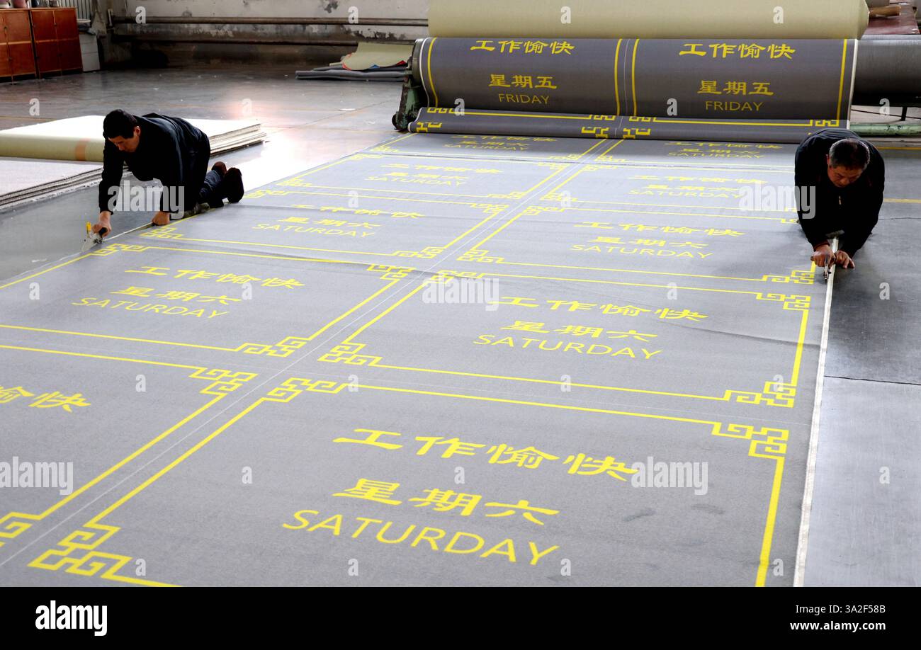 Workers cut out carpets at a carpet factory in Yangxin county in east ...