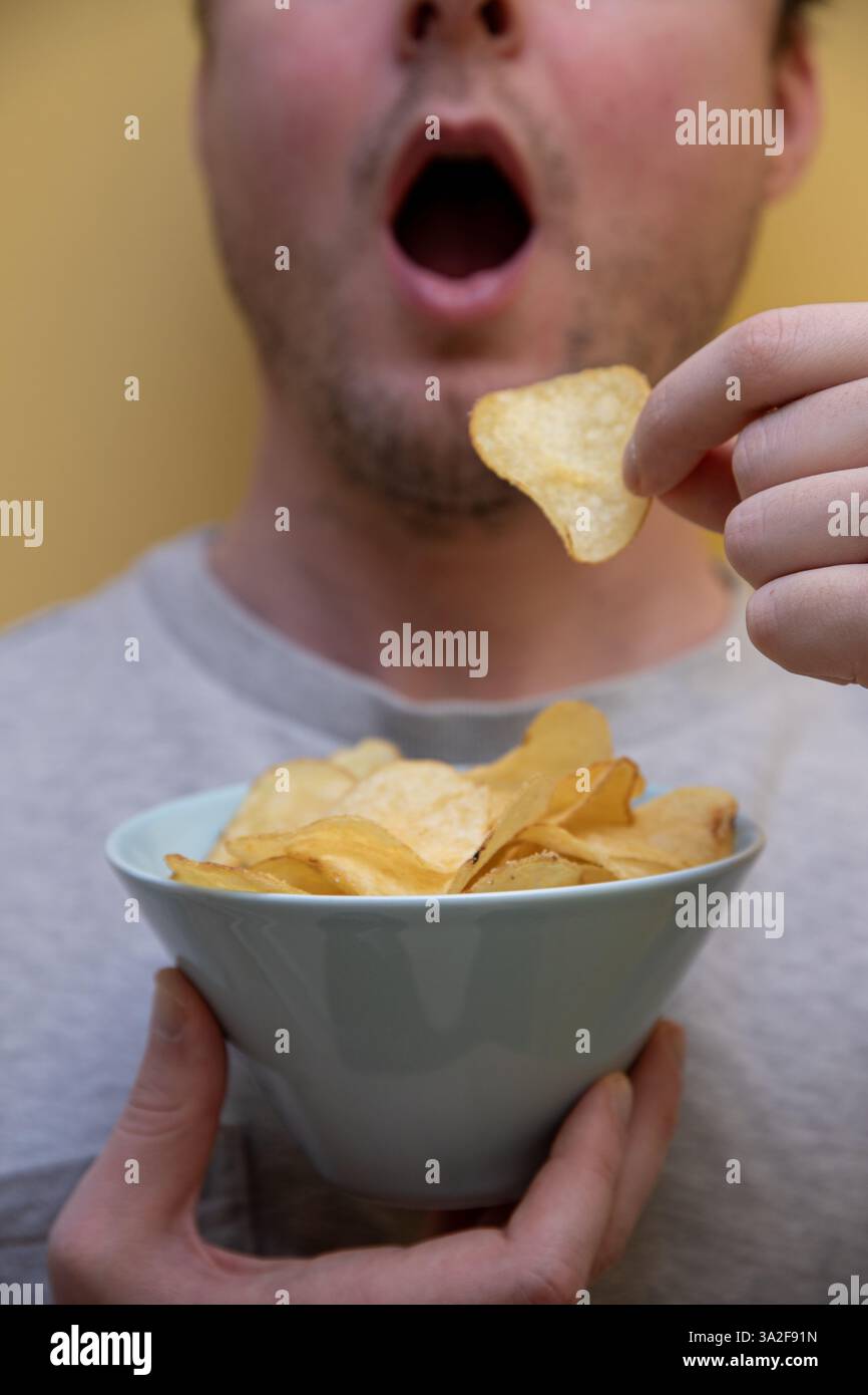 a man eating potato chips. unhealthy eating concept Stock Photo - Alamy