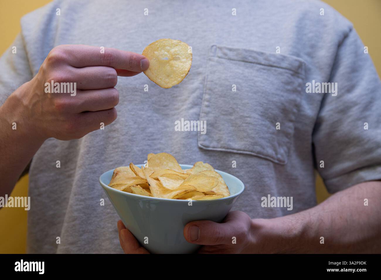 a man eating potato chips. unhealthy eating concept Stock Photo - Alamy