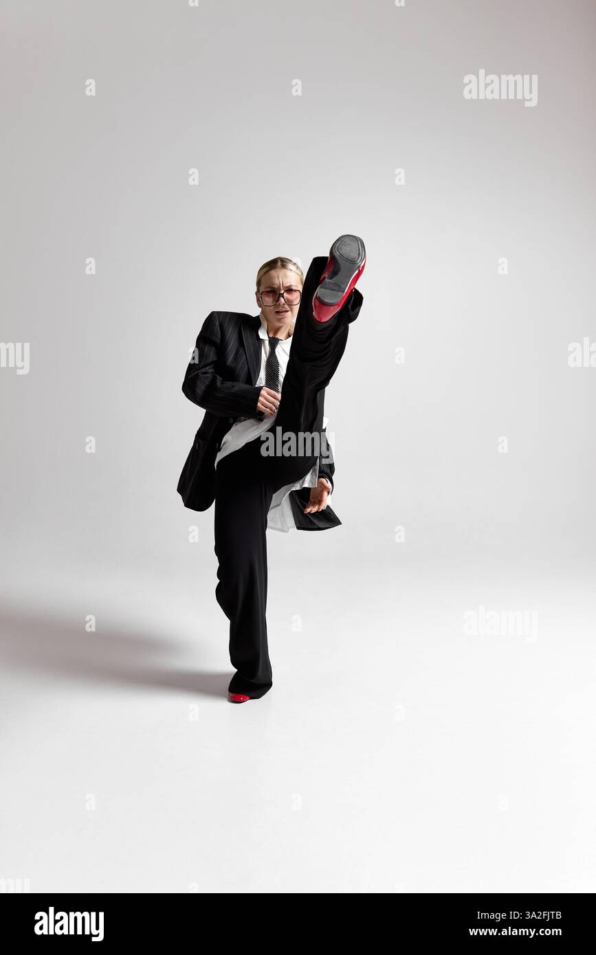 Dynamic photo of powerful high kick of young woman in bold business ...