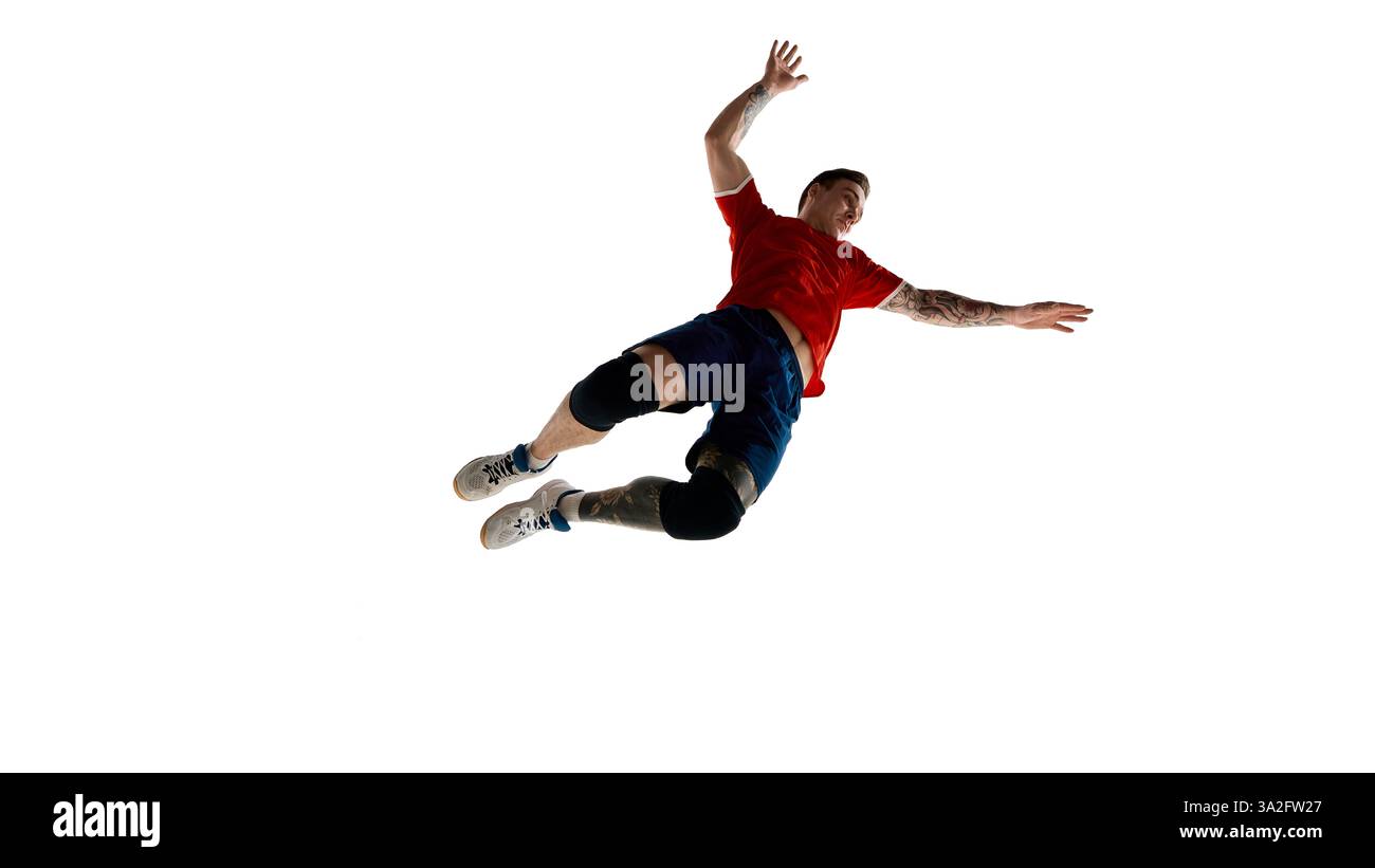 Young guy in red jersey and blue shorts, volleyball player in motion ...
