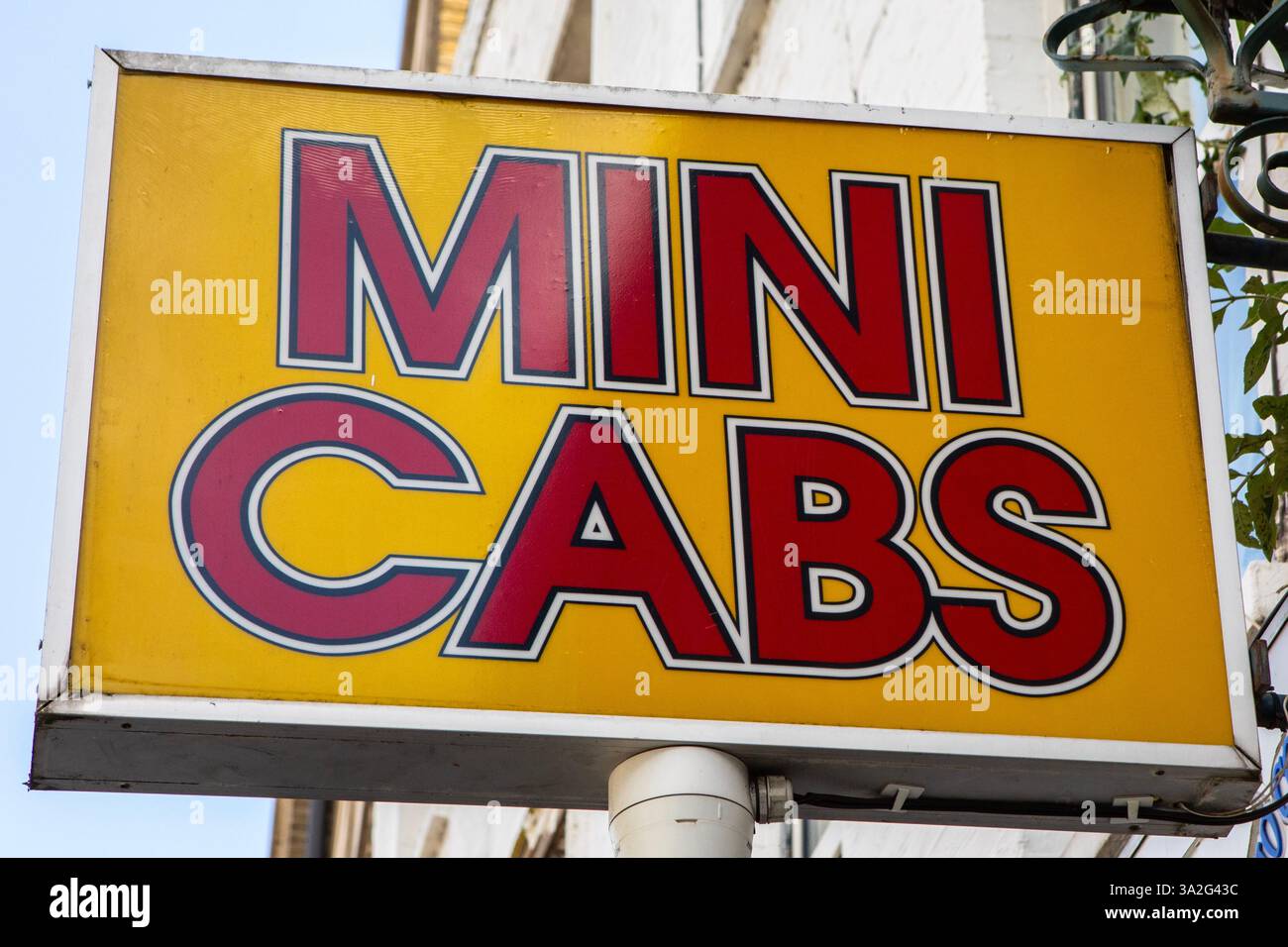 Close-up of a Mini Cabs sign on the exterior of a building in the UK ...