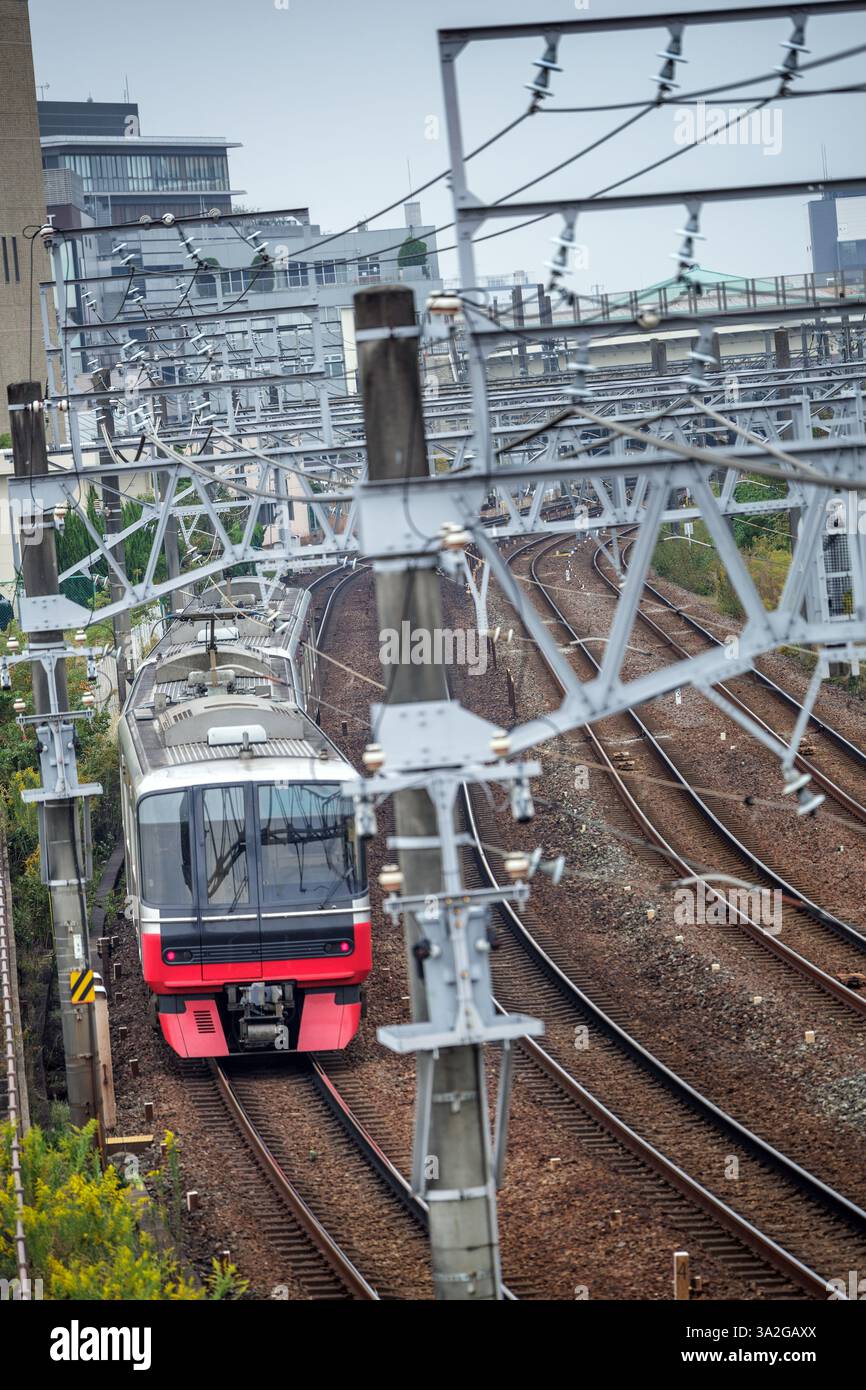 Rush hour red commuter train reflects overhead aluminum structures and ...