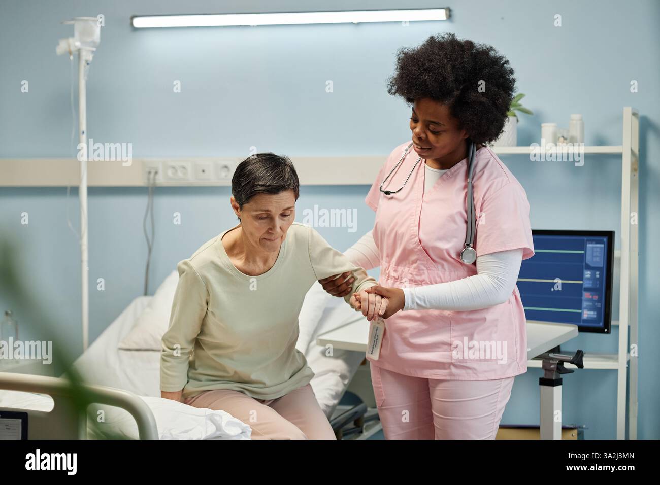 Nurse helping senior patient sit up on bed in hospital room focused on ...