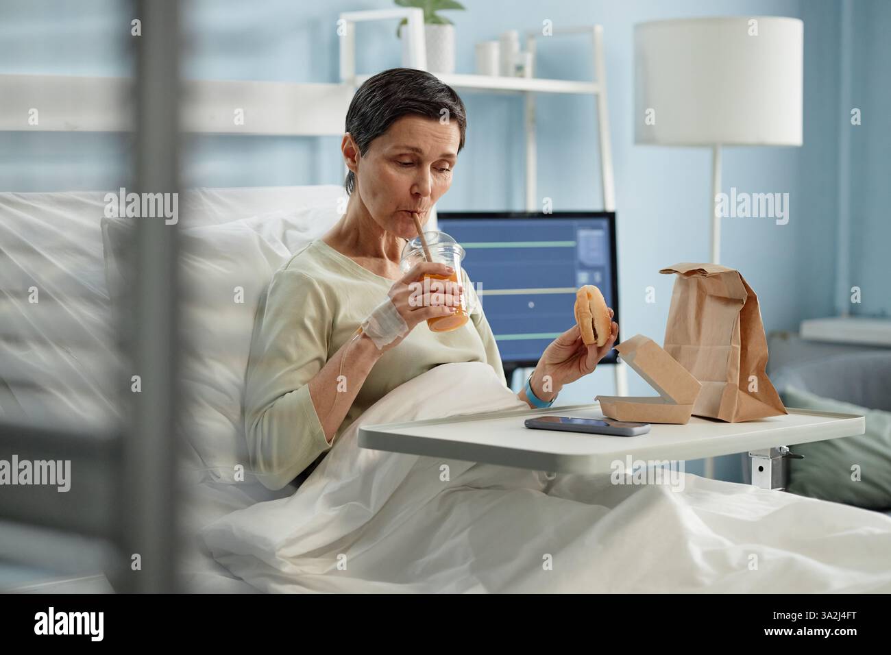 Portrait of elderly woman in hospital room eating breakfast from tray ...
