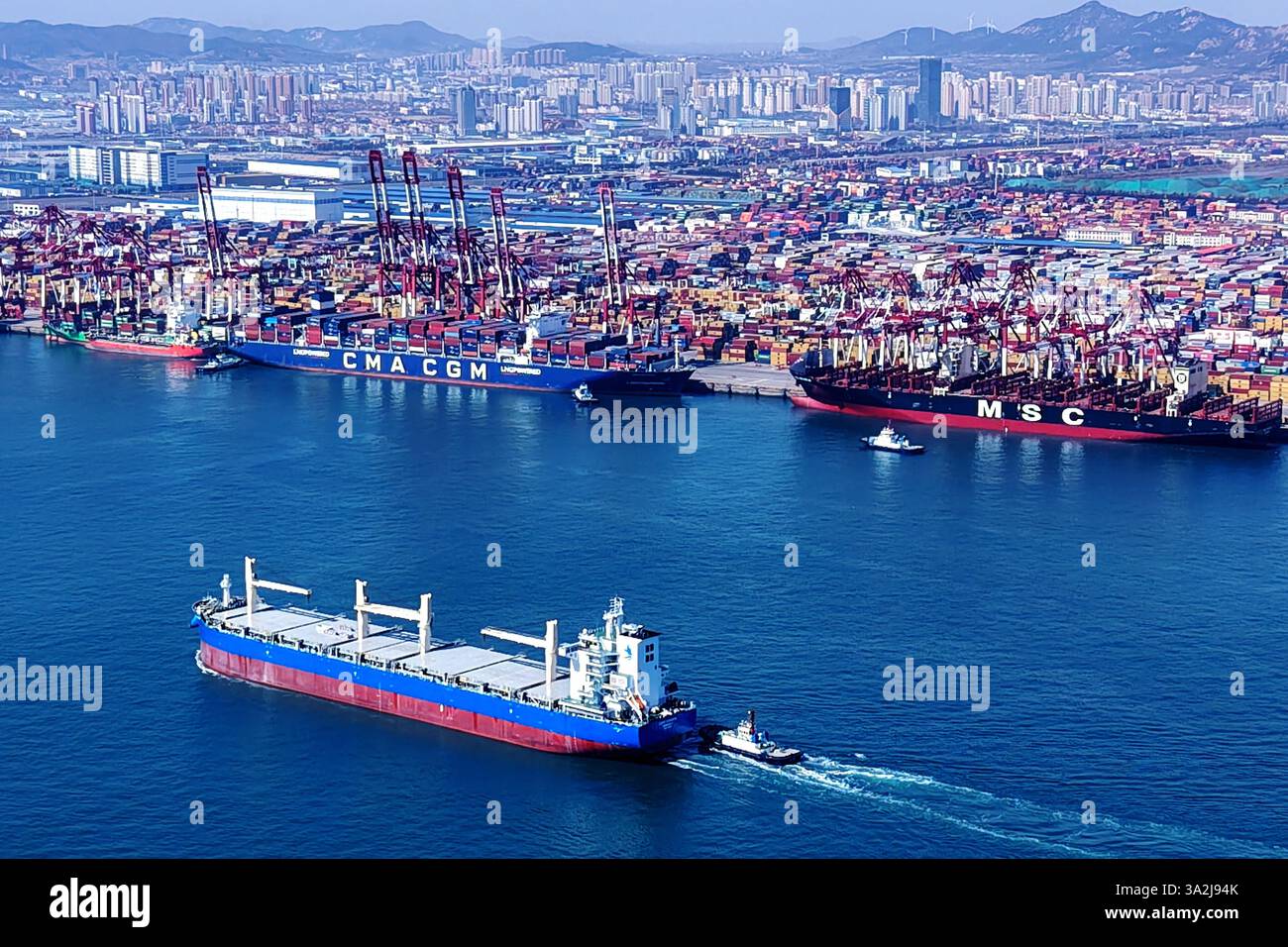 A general cargo ship sails into the port of Qingdao, a port in Shandong ...