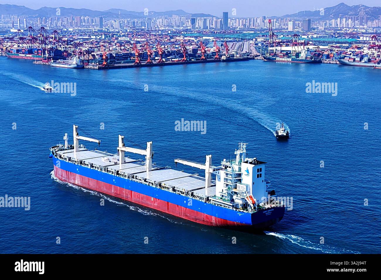 A general cargo ship sails into the port of Qingdao, a port in Shandong ...