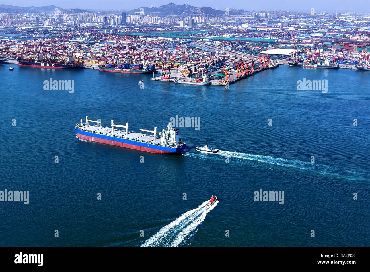 A general cargo ship sails into the port of Qingdao, a port in Shandong ...