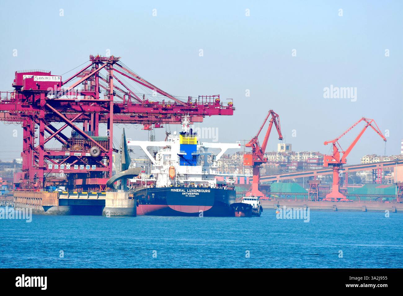 A cargo ship offloads imported iron ore at Qingdao Port in Shandong ...