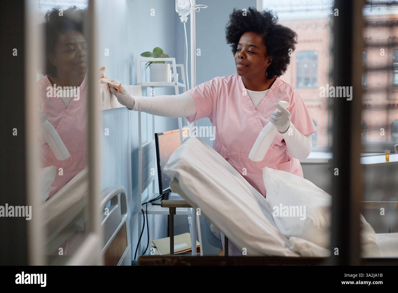Nurse cleaning hospital room by disinfecting surface with spray ...