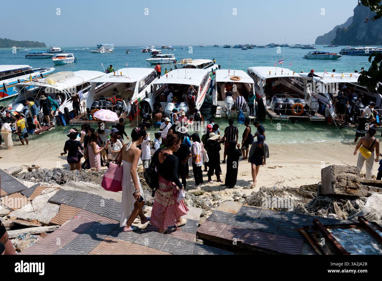 Tourists step onto the sandy shore as a multitude of speedboats are ...