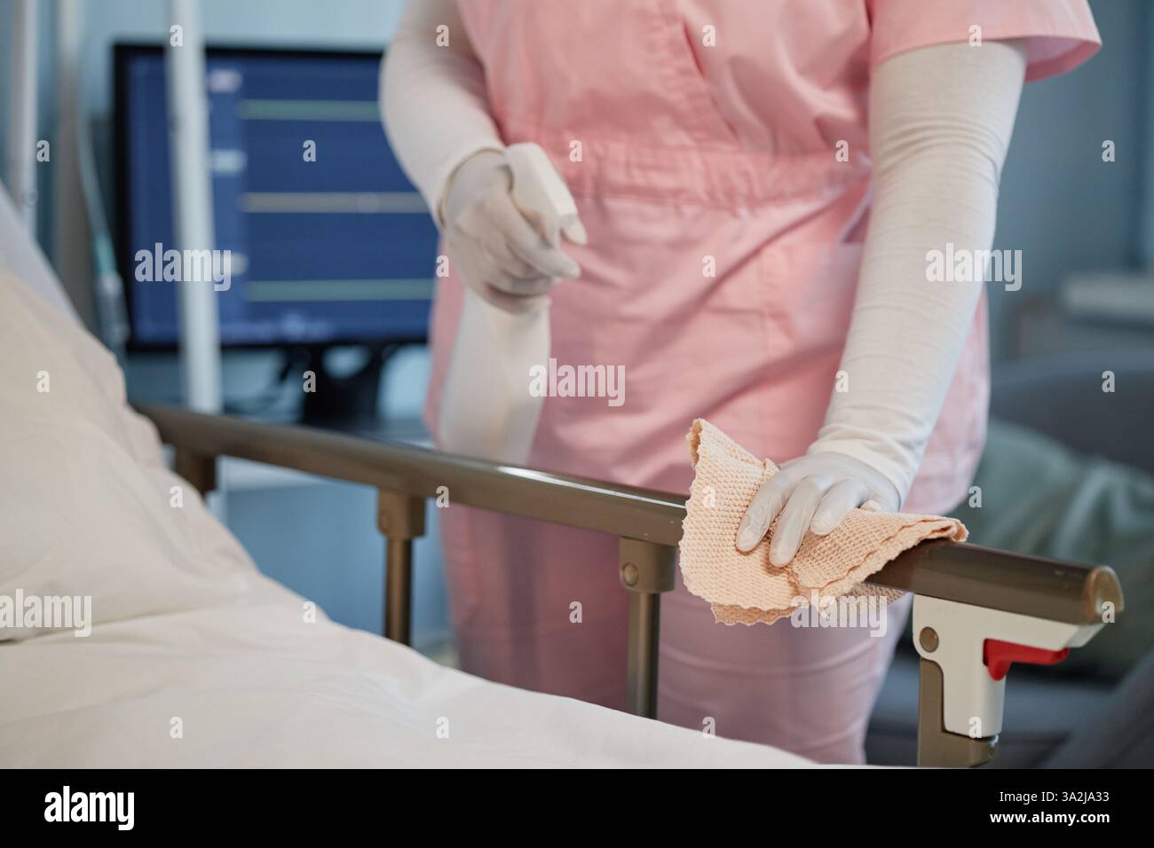 Nurse wearing pink uniform cleaning hospital bed with a cloth in a ...
