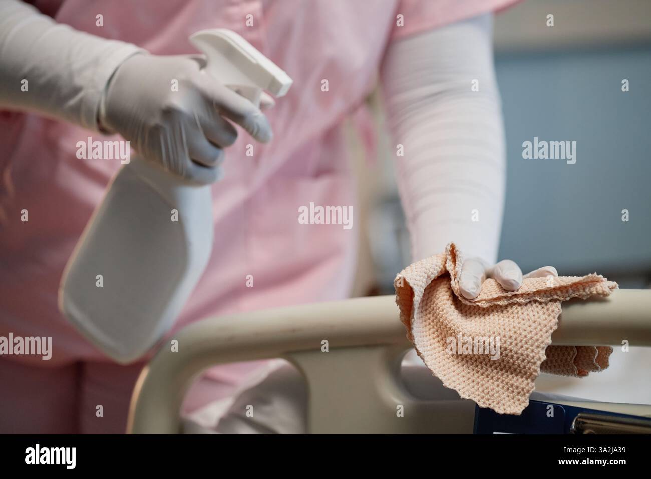 Hospital staff member cleaning hospital bed using disinfectant spray ...