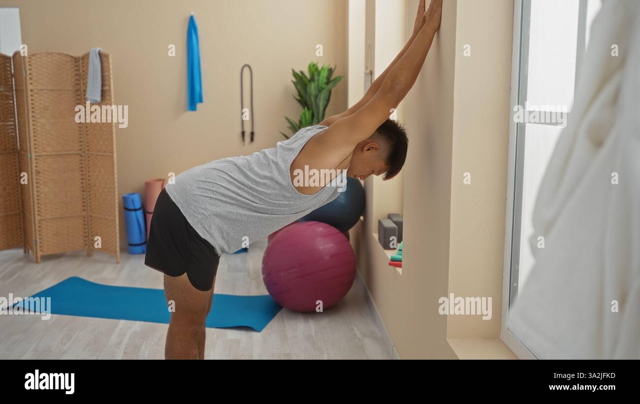 Young chinese man stretching in a wellness room at a spa with exercise ...