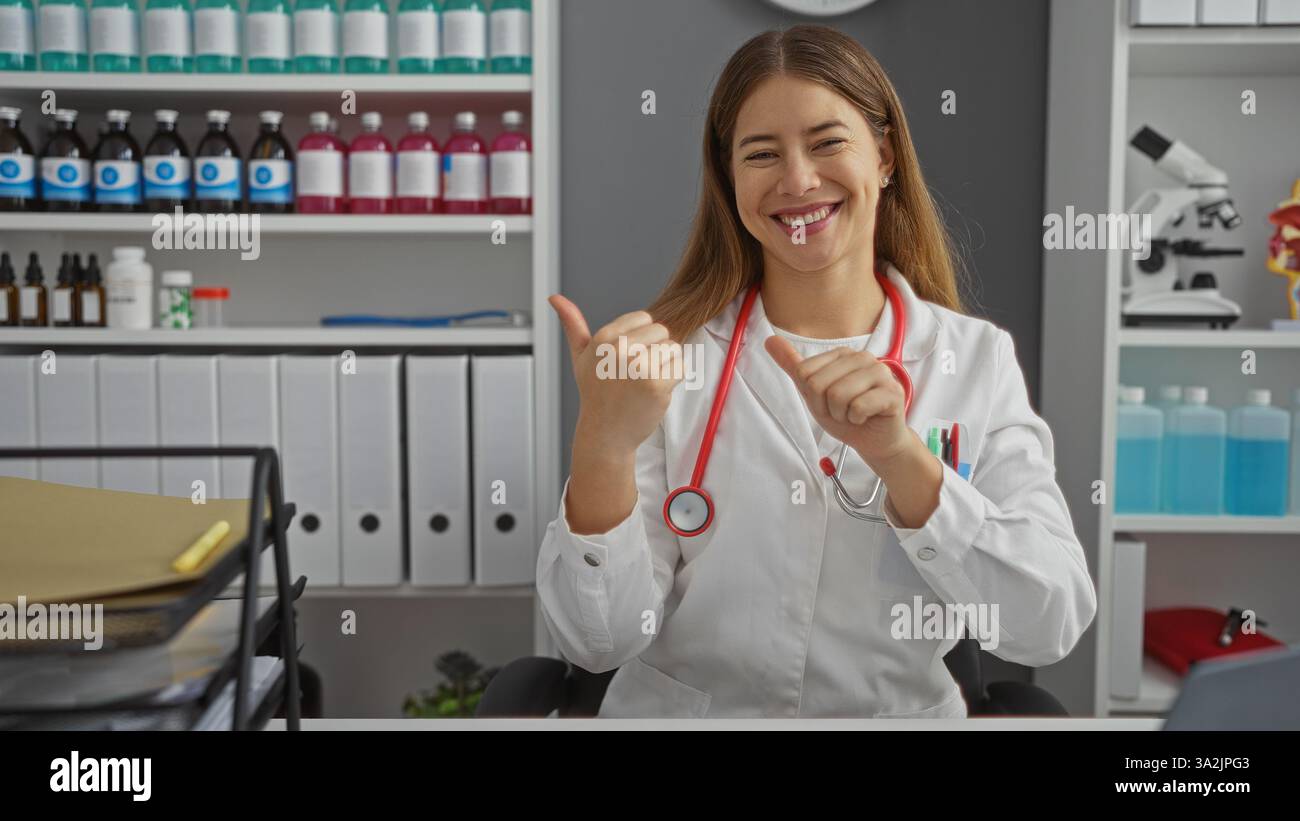 Woman in a lab coat in a clinic room smiles, pointing her thumbs ...