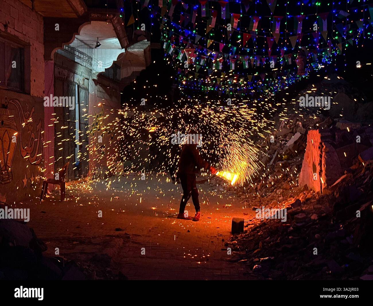 Palestinian youths light fireworks near the rubble of a building to ...