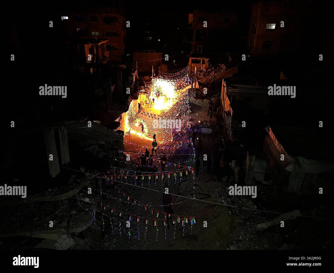 Palestinian youths light fireworks near the rubble of a building to ...