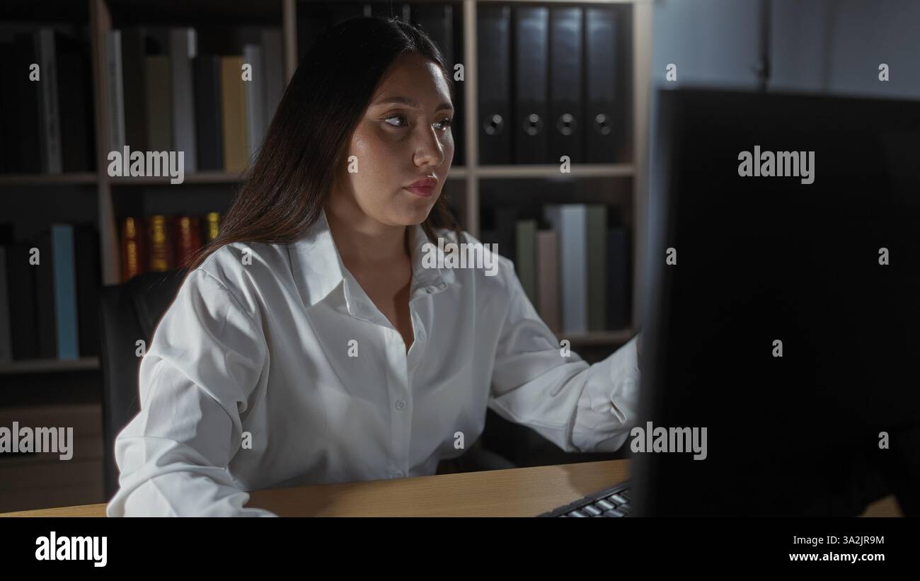 Woman working on computer in indoor office with bookshelves and binders ...