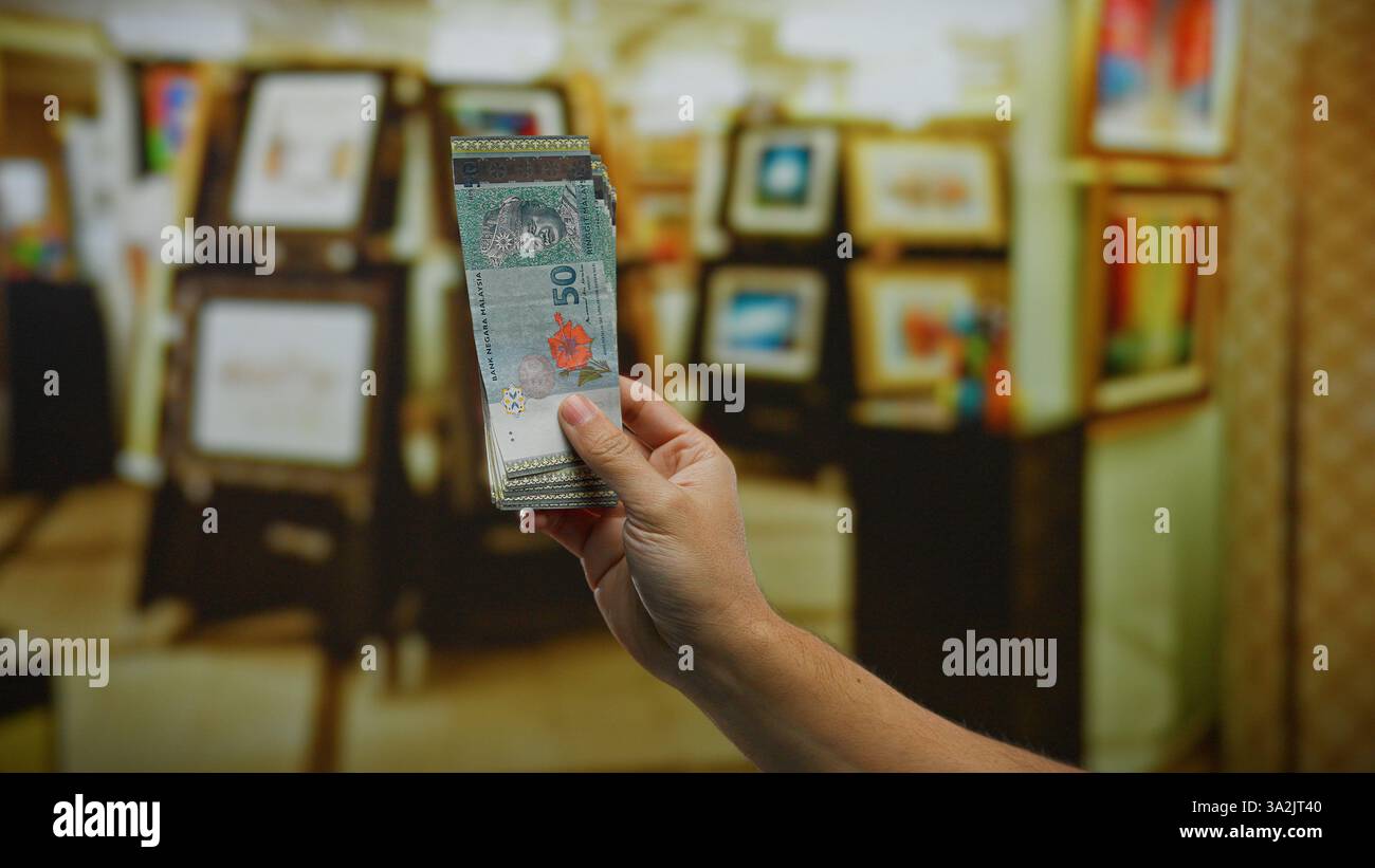 Man holding malaysian ringgit banknotes in an art exhibition room ...