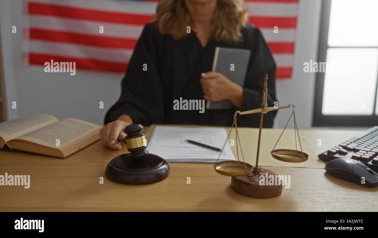 Judge woman seated at a desk in a courtroom holding a book with the ...