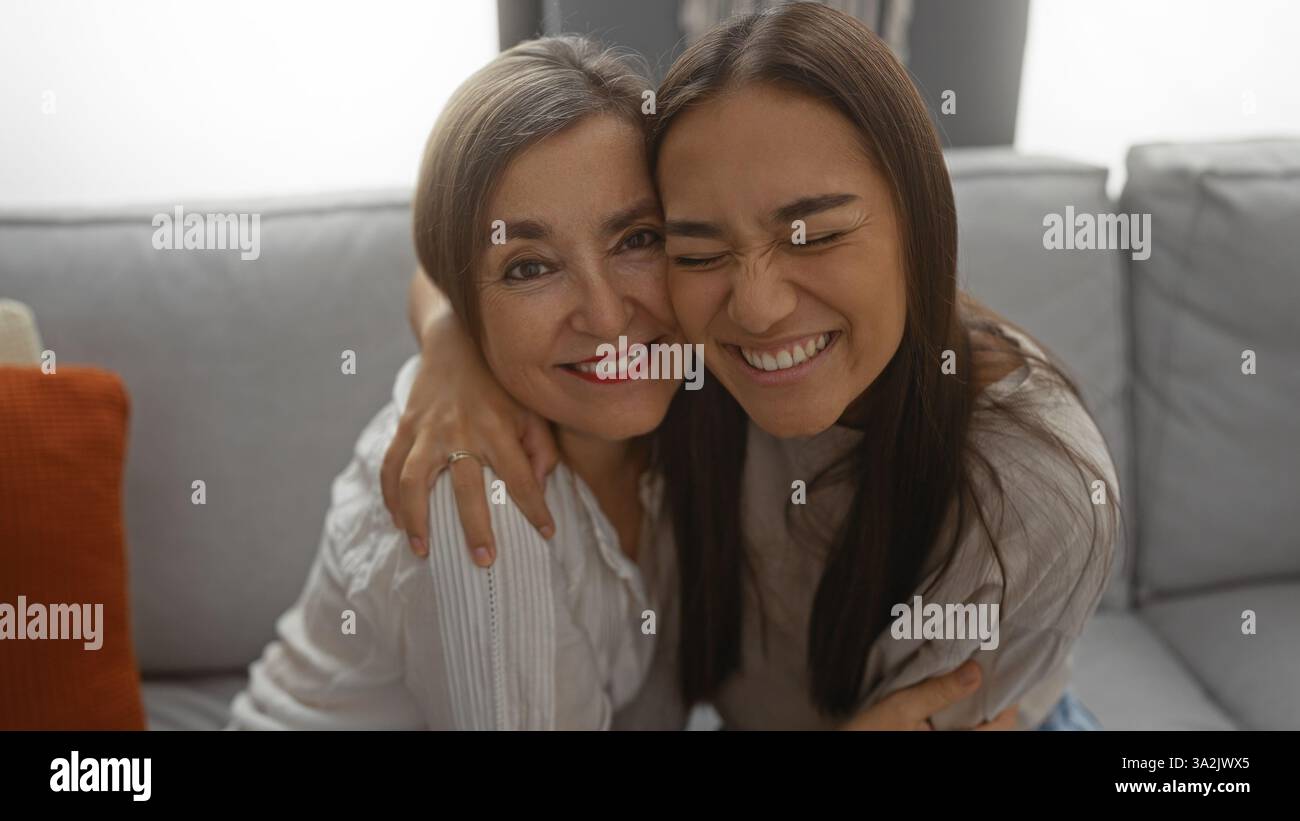 Mother and daughter sharing a loving embrace while sitting on a sofa in ...