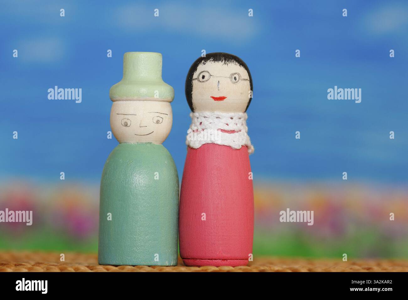 Two funny painted wooden cones man and woman in front of a colourful ...