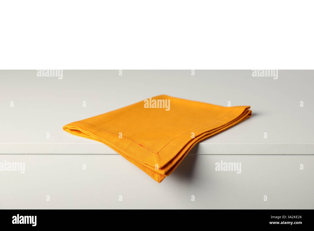 Orange napkin on light table against white background Stock Photo - Alamy