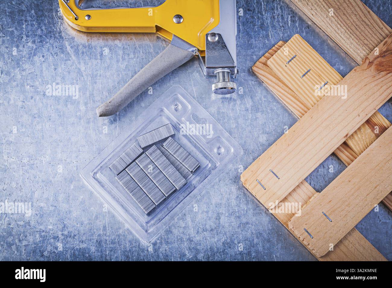 Set of stapler gun chrome staples wooden building board on metallic ...