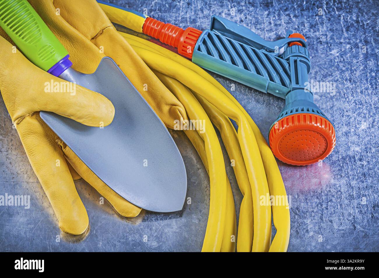 Set of rubber garden hose spray nozzle safety gloves spade on metallic ...