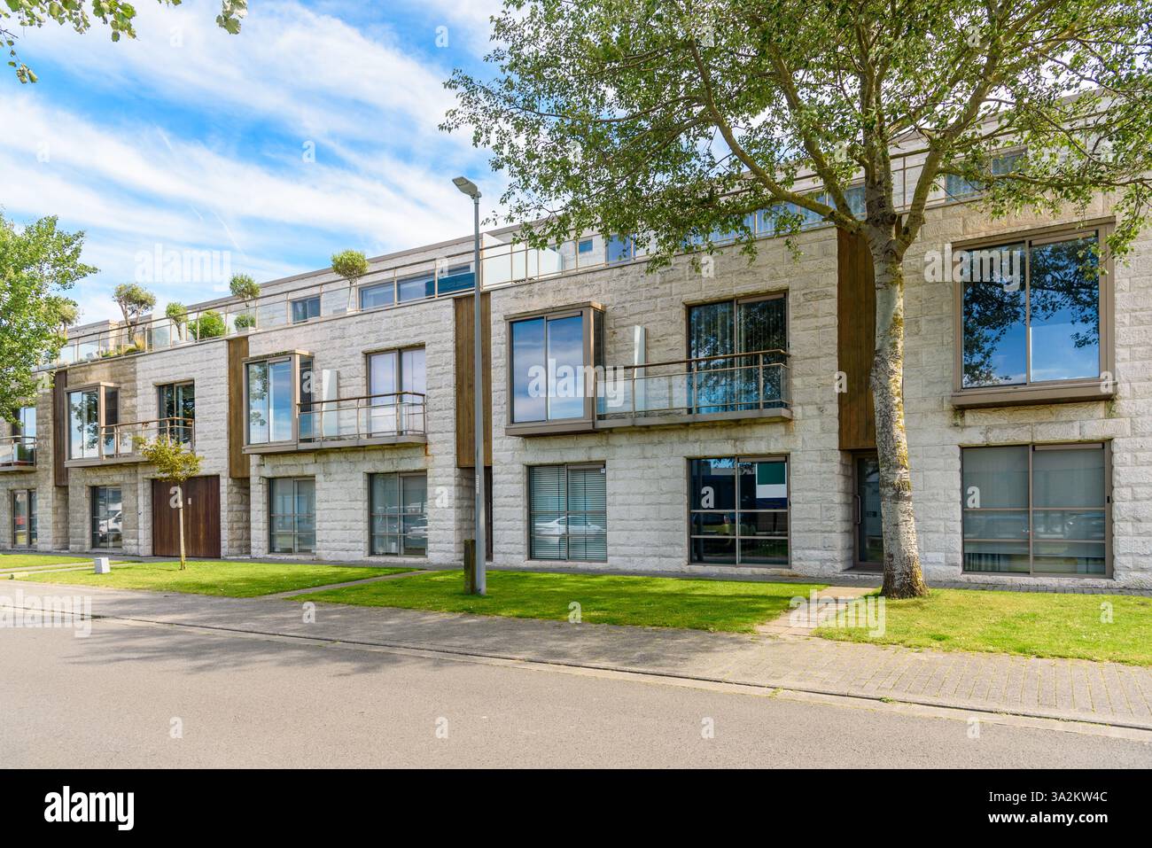 Row of new terraced houses with glass railing rooftop terraces along a ...