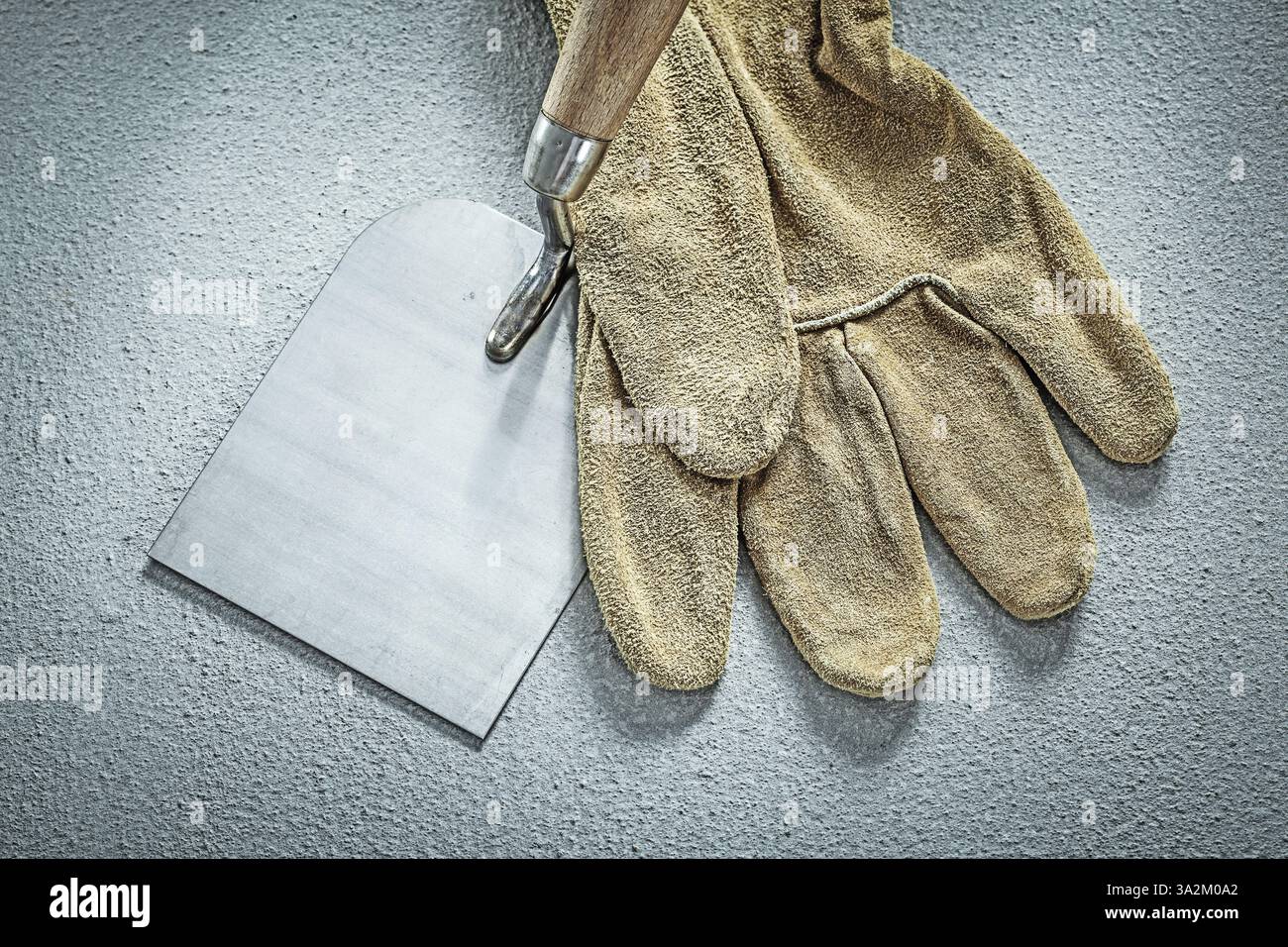 Stainless putty knife safety glove on concrete background construction ...