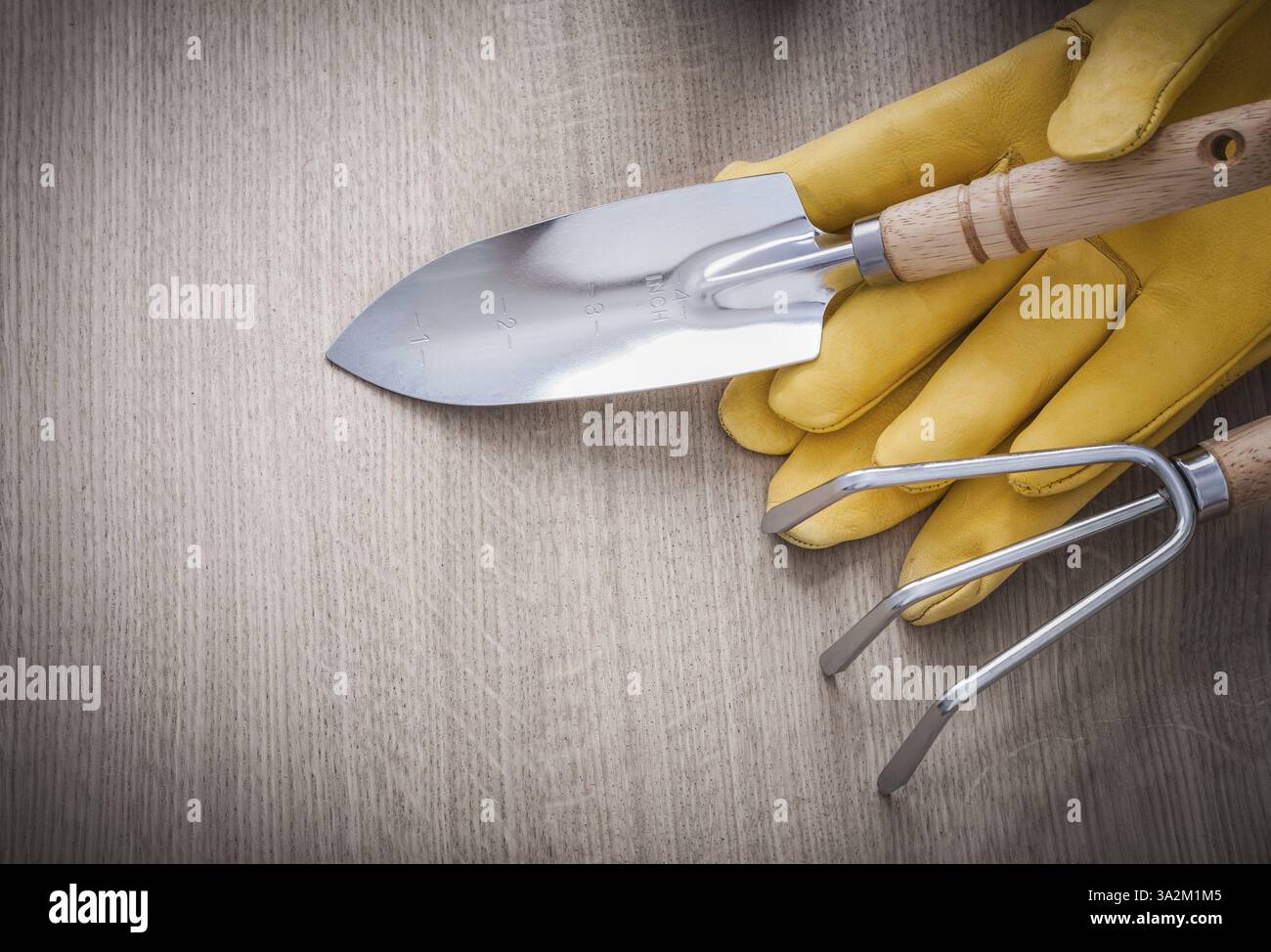 Stainless hand spade rake yellow leather gardening gloves on wood board ...