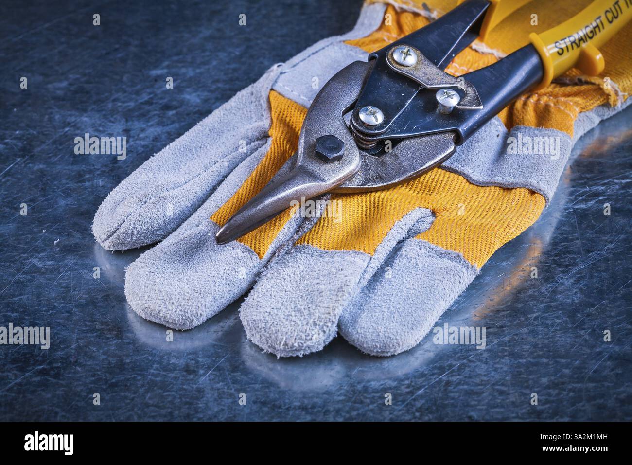 Safety gloves with tin snips on scratched vintage metallic background ...