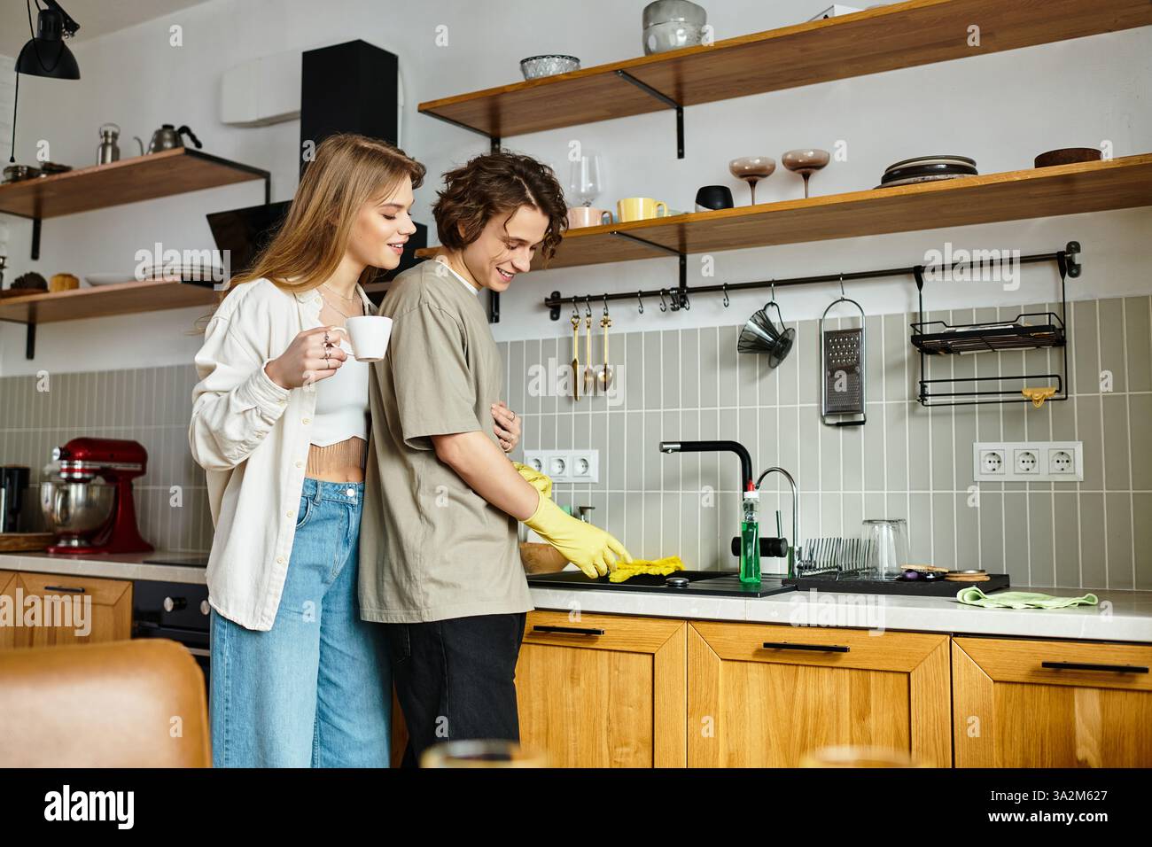 Two young individuals share laughter and love while washing dishes in ...