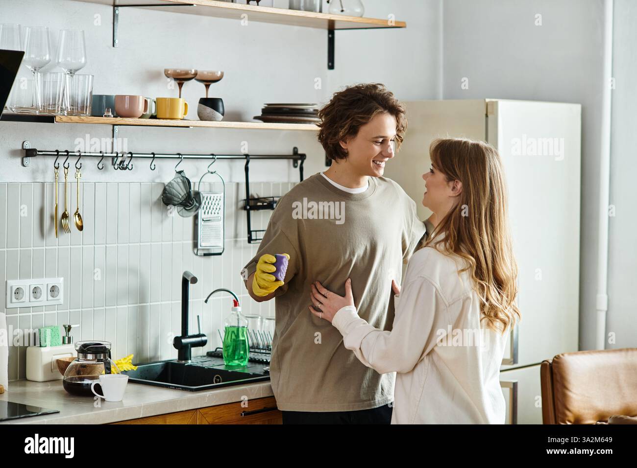 A loving couple embraces in their stylish kitchen, enjoying a warm and ...