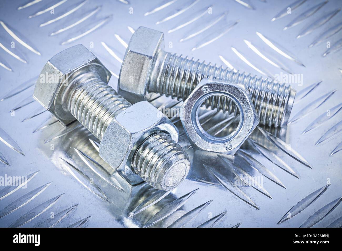 Stainless bolts and construction nuts on grooved metal sheet top view ...